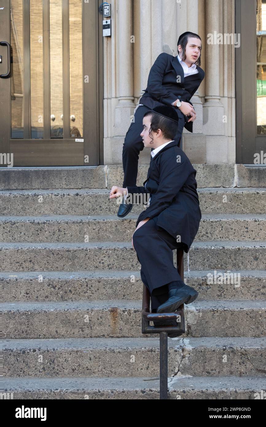 On a warm winter day, 2 hasidic yeshiva students relax during recess on ...