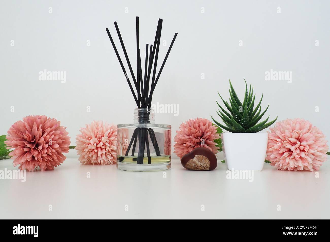 Composition of pink artificial flowers, incense sticks in a glass vase ...