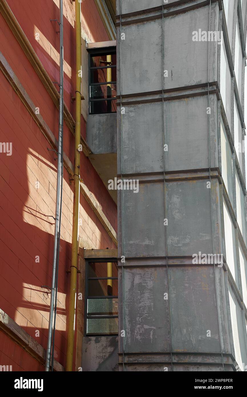 Gray metal construction elevator attached to a red building, used for ...