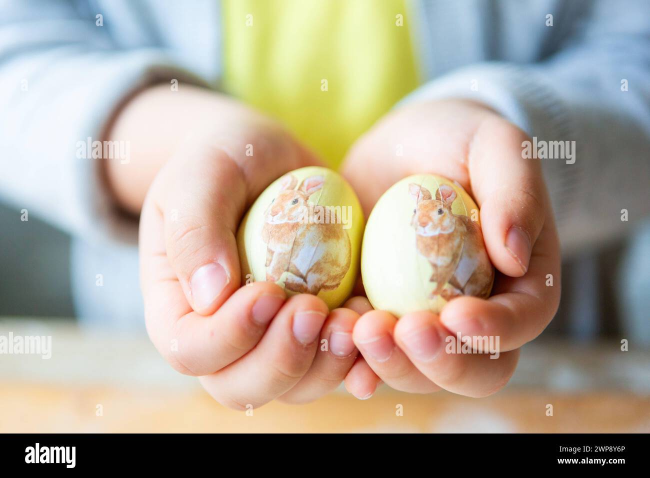 3 March 2024: Child holding a present for Easter. Two Easter eggs with ...