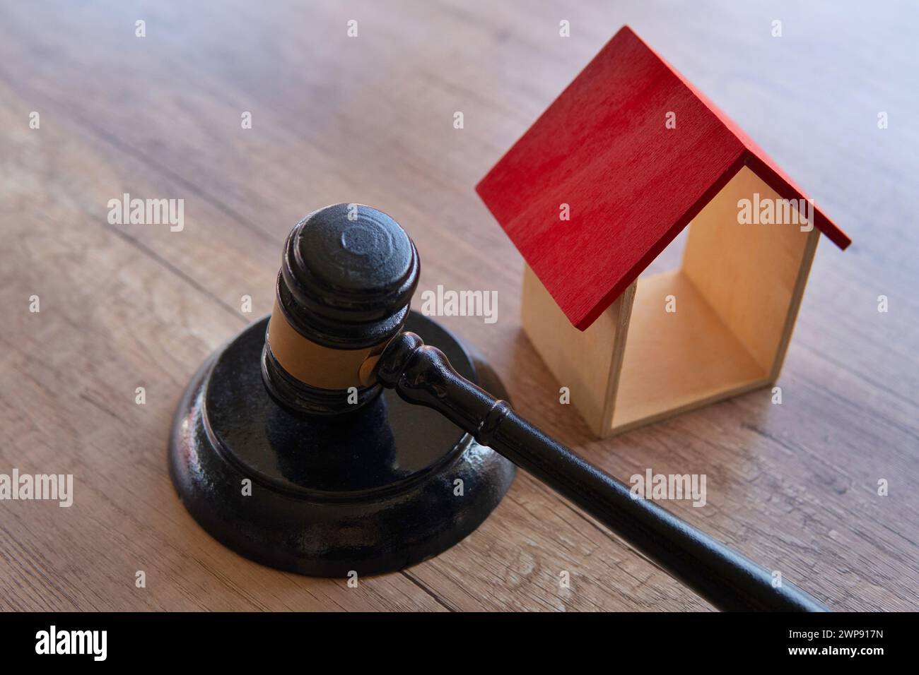 Closeup image of gavel next to miniature wooden house. House auction ...