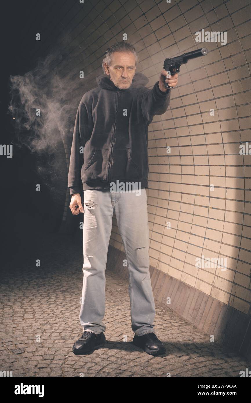 Old member of criminal gang armed with handgun shooting in gun smoke ...