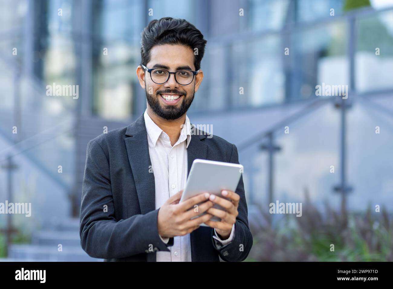 A young businessman in a smart suit engrossed in using his tablet ...