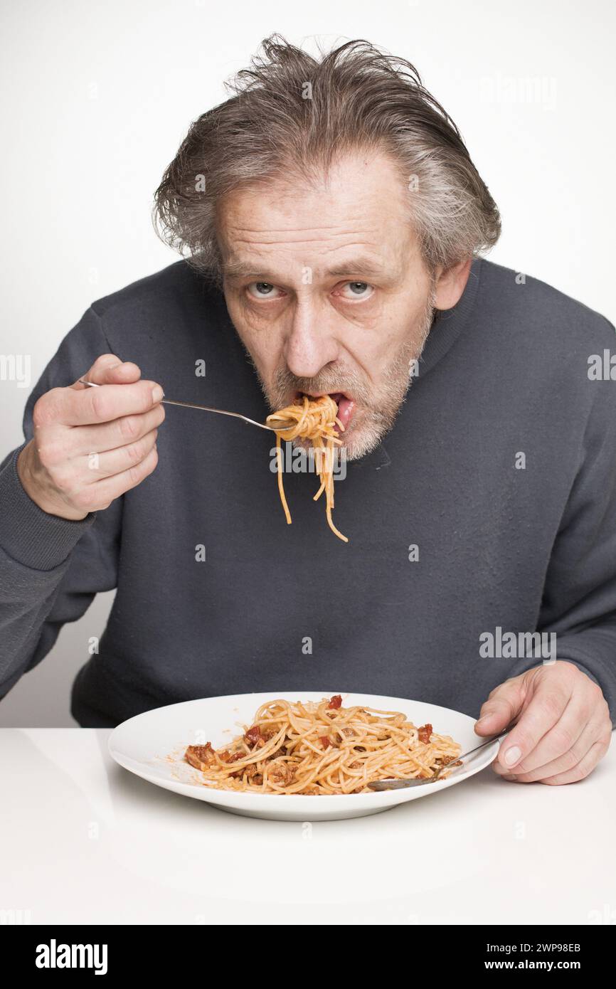 Older man eating spaghetti with minced meat, tomatoes and cheese Stock ...