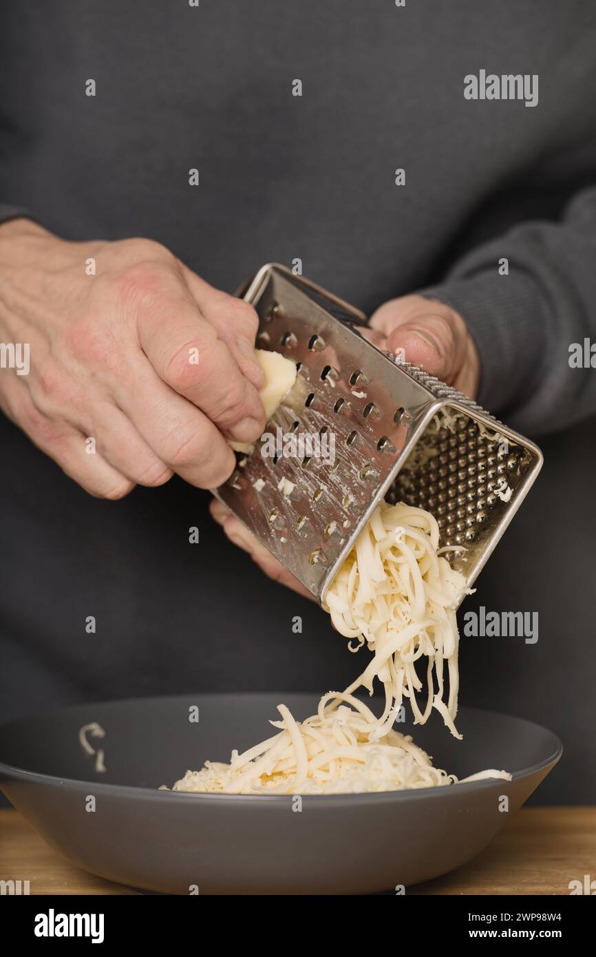 Older man in kitchen grating cheese for spaghetti with minced meat ...