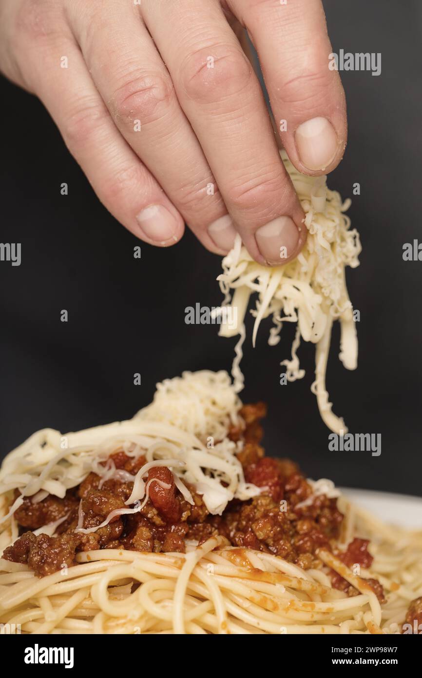 Older man in kitchen grating cheese for spaghetti with minced meat ...