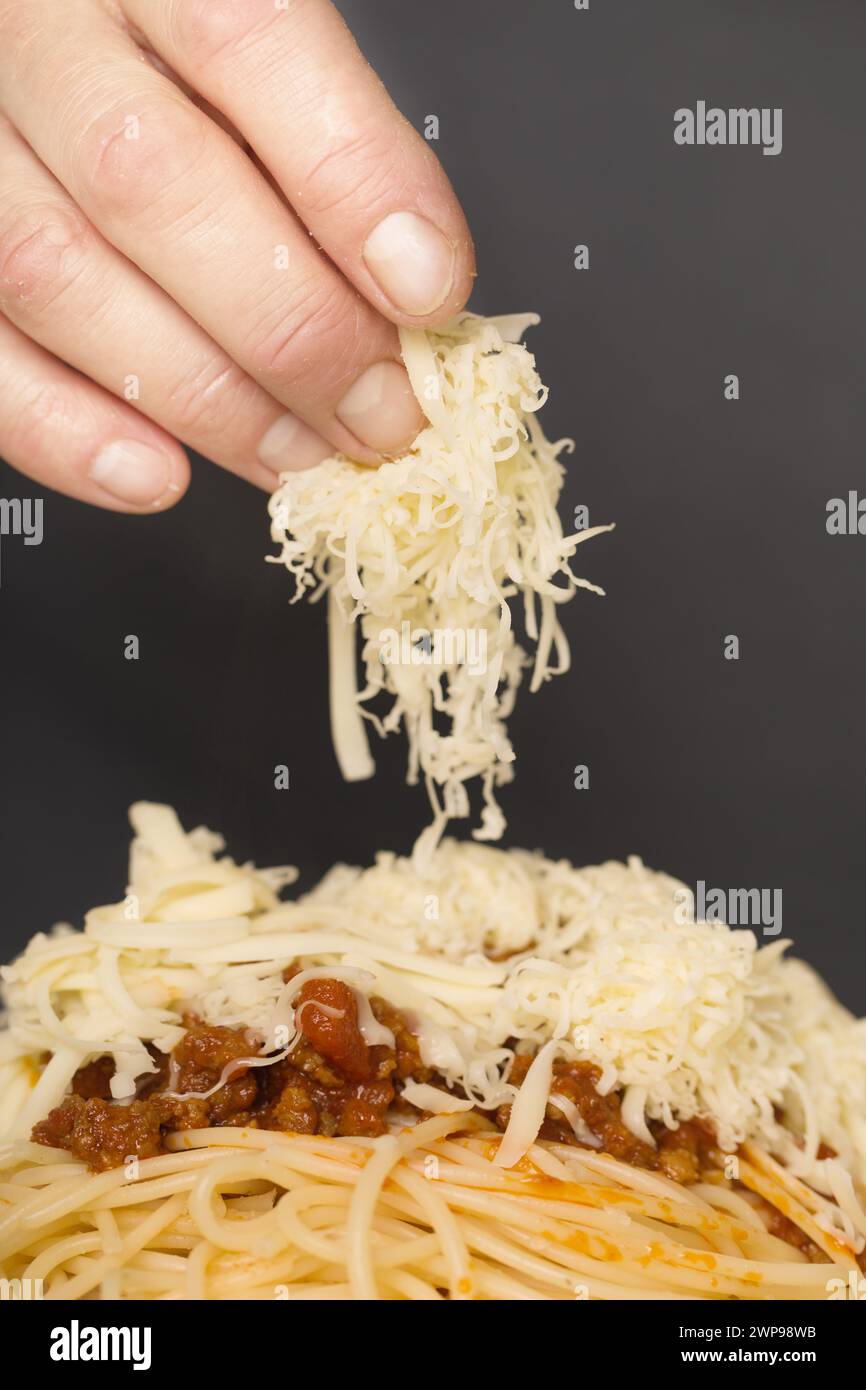 Older man in kitchen grating cheese for spaghetti with minced meat ...