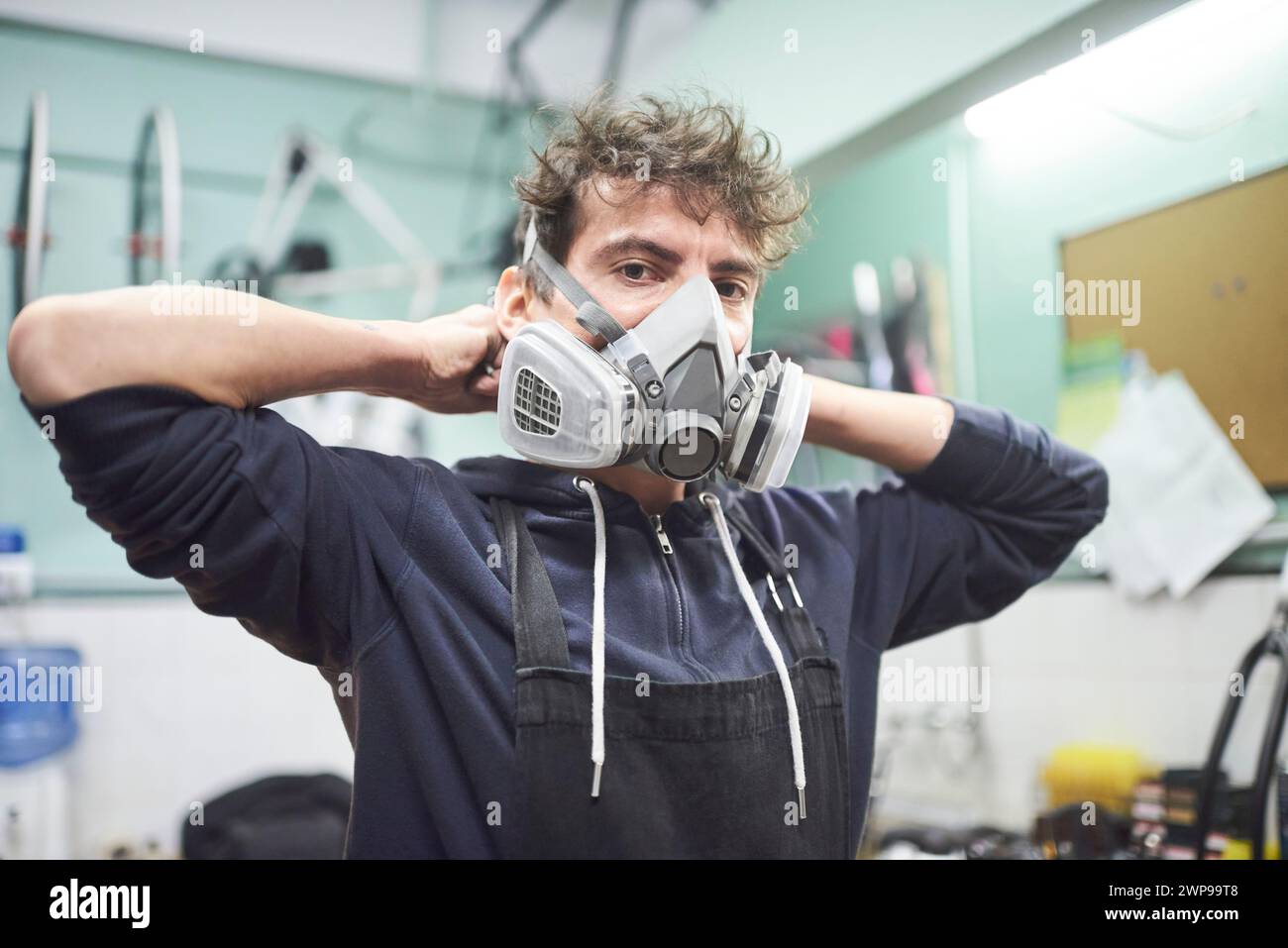Portrait of a latin young worker adjusting a respiratory protection ...