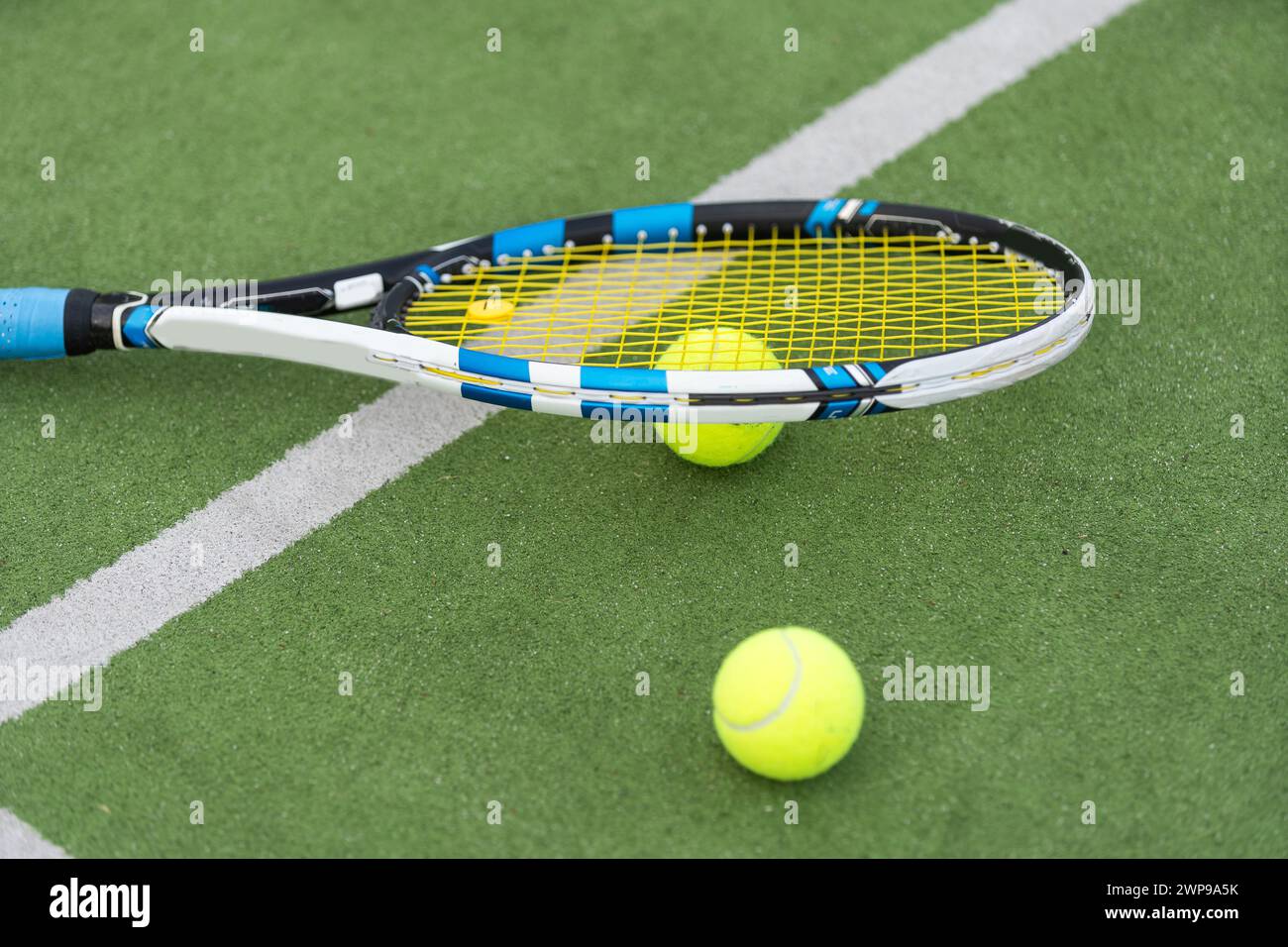Tennis ball and racket on the ground of sunny outdoor grass tennis ...