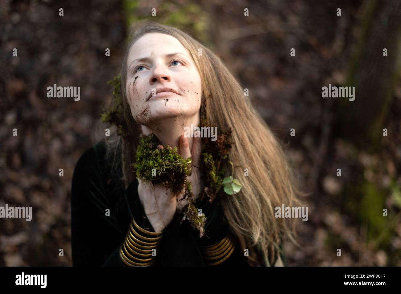 Female shaman performs a nature ritual by smearing her face with forest ...