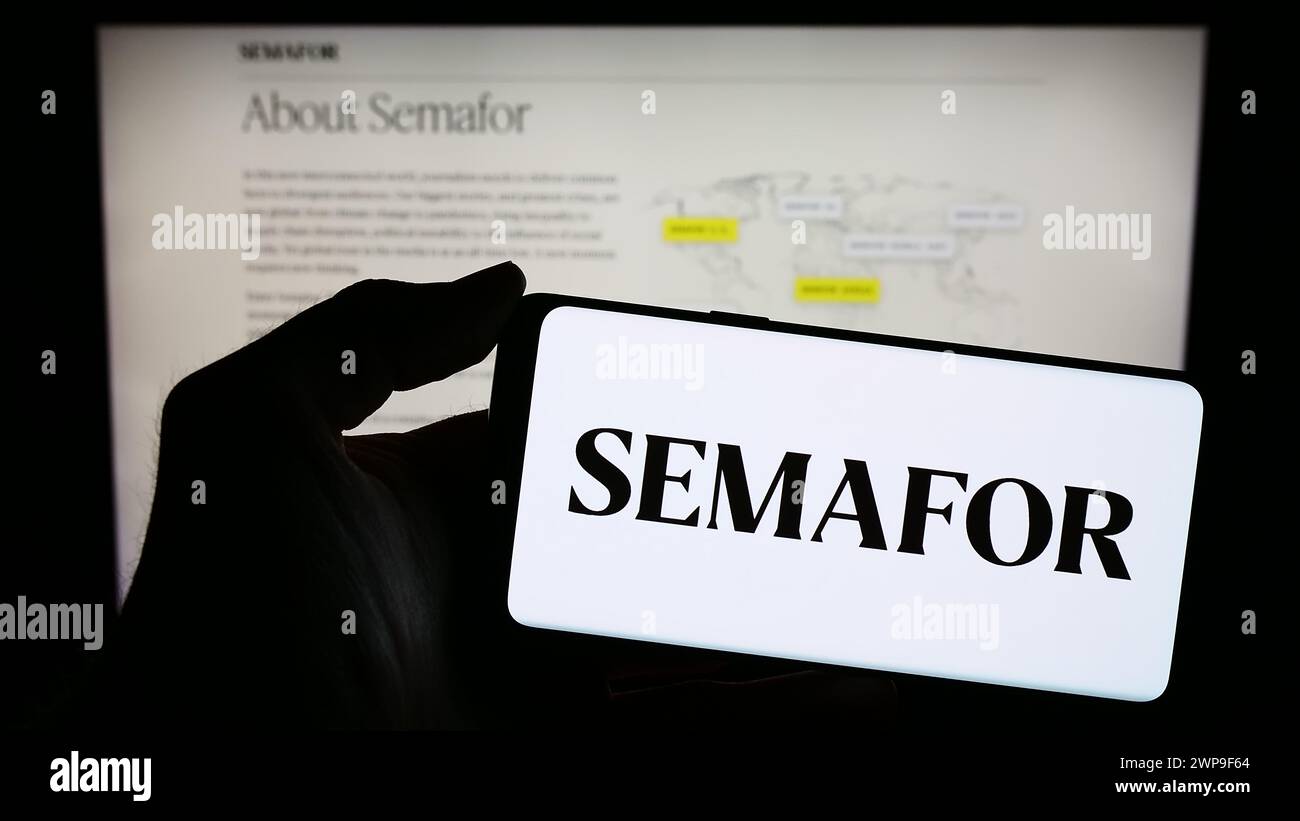 Person holding mobile phone with logo of American media company Semafor ...