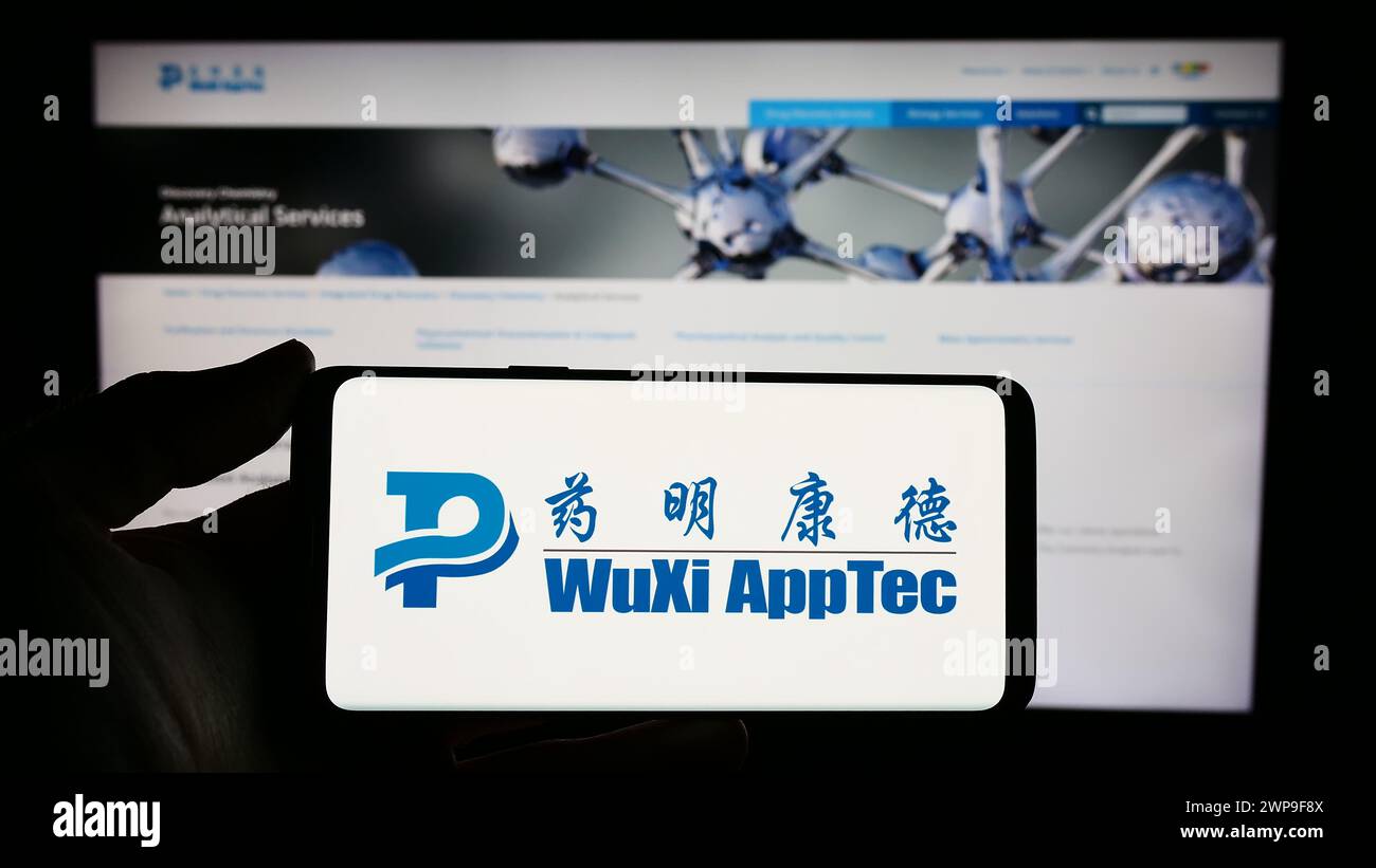 Person holding cellphone with logo of Chinese pharmaceutical company ...