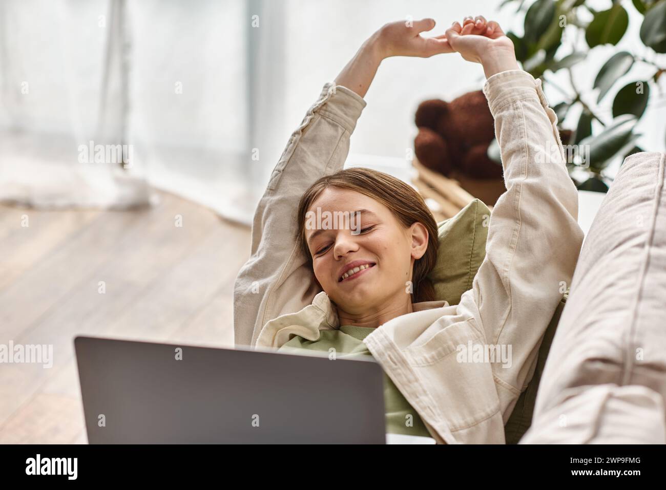 cheerful teenage girl lying with her laptop and stretching on ...