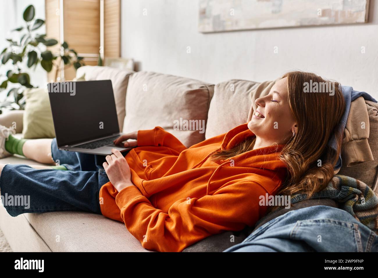 happy teenager girl watching comedy movie on a laptop with blank screen ...
