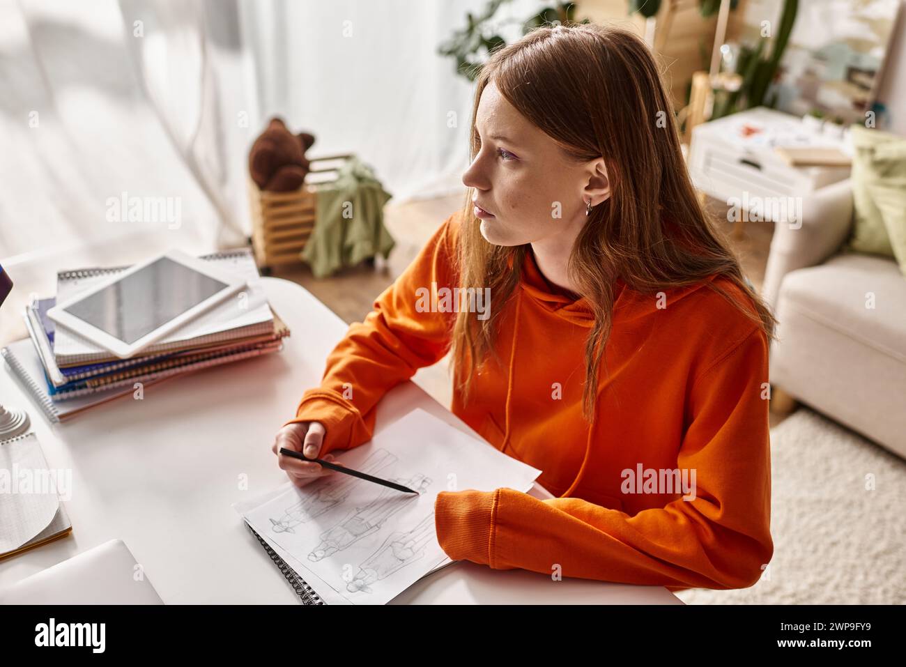 pensive teenage girl drawing a sketch, immersed in creative process ...
