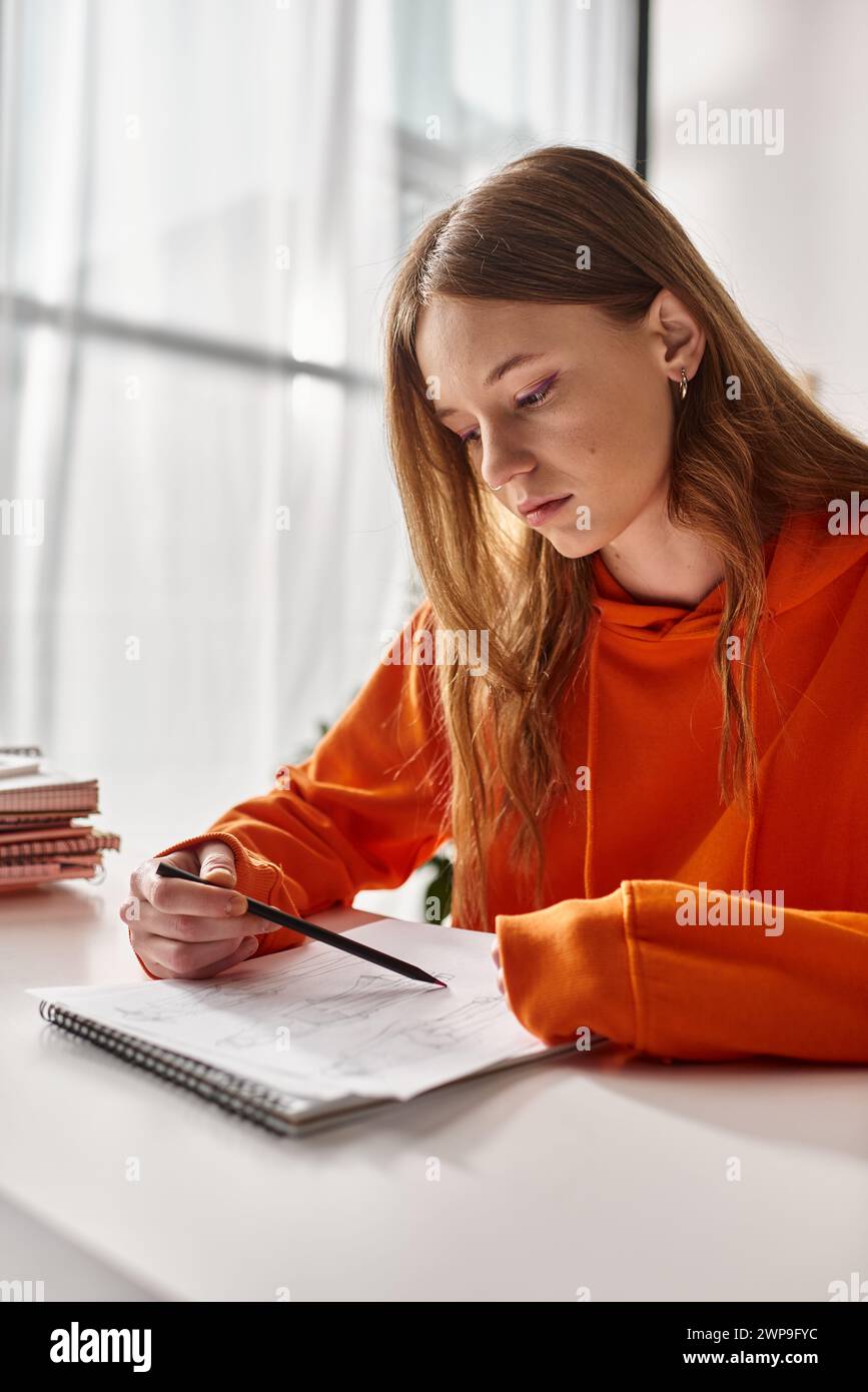 pensive teenage girl drawing a sketch, immersed in creative process ...