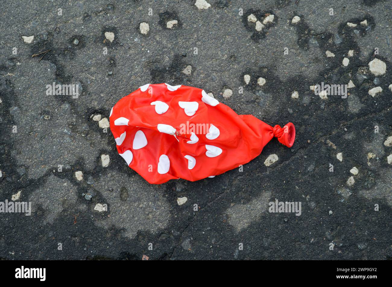 A discarded and deflated red valentine's day balloon lying on a pavement Stock Photo - Alamy