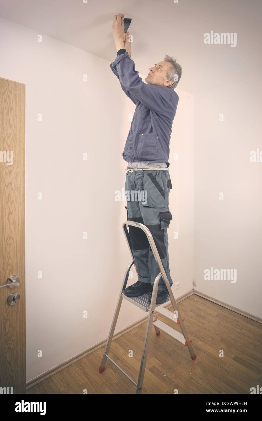 Older man repairing walls and ceiling in empty apartment Stock Photo ...