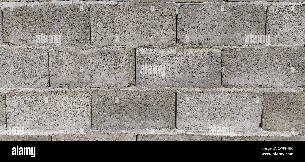 Wall of uneven gray cement blocks. Concrete fence or structure. The ...