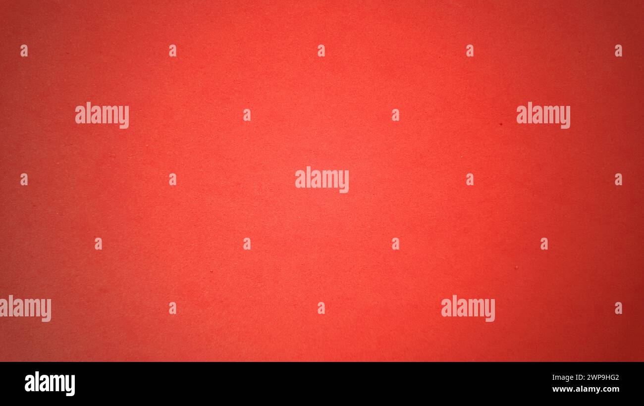 A sheet of bright red paper with light vignetting around the edges ...