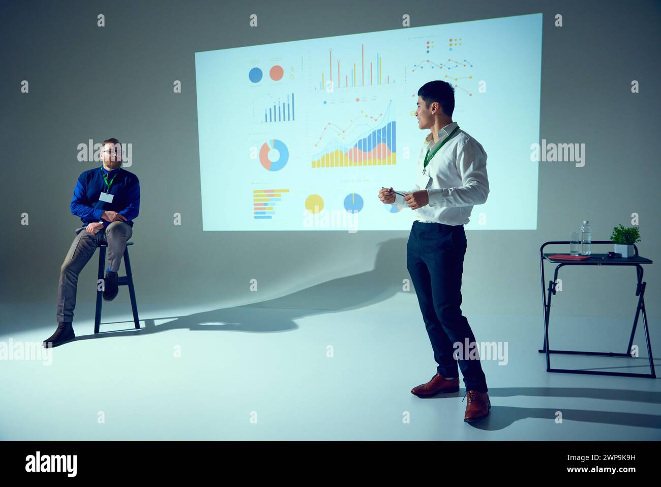 Two men present at business meeting, one seated listening, other ...