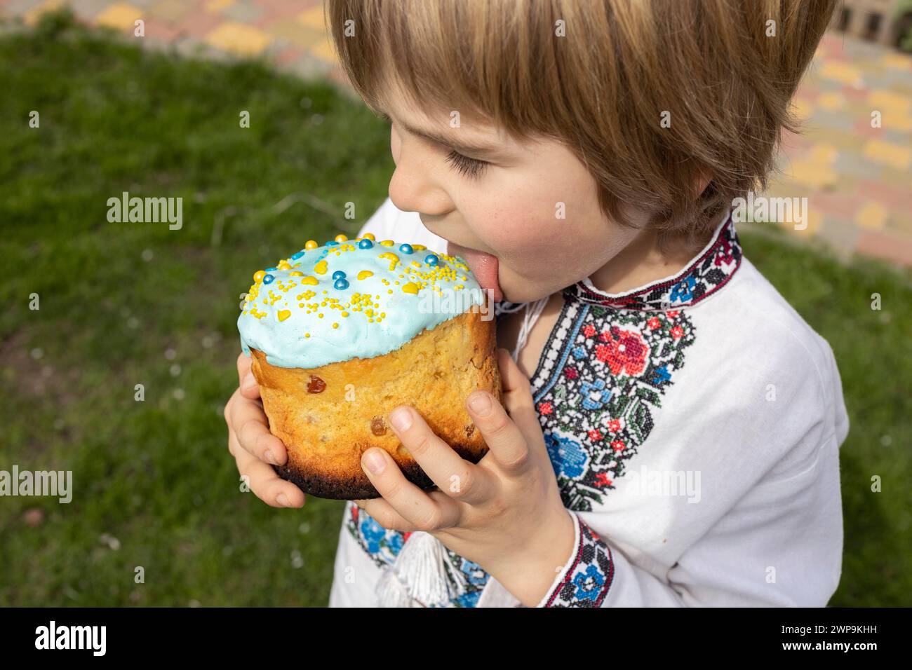boy tastes the sweet icing from the paska. A Ukrainian child in an ...