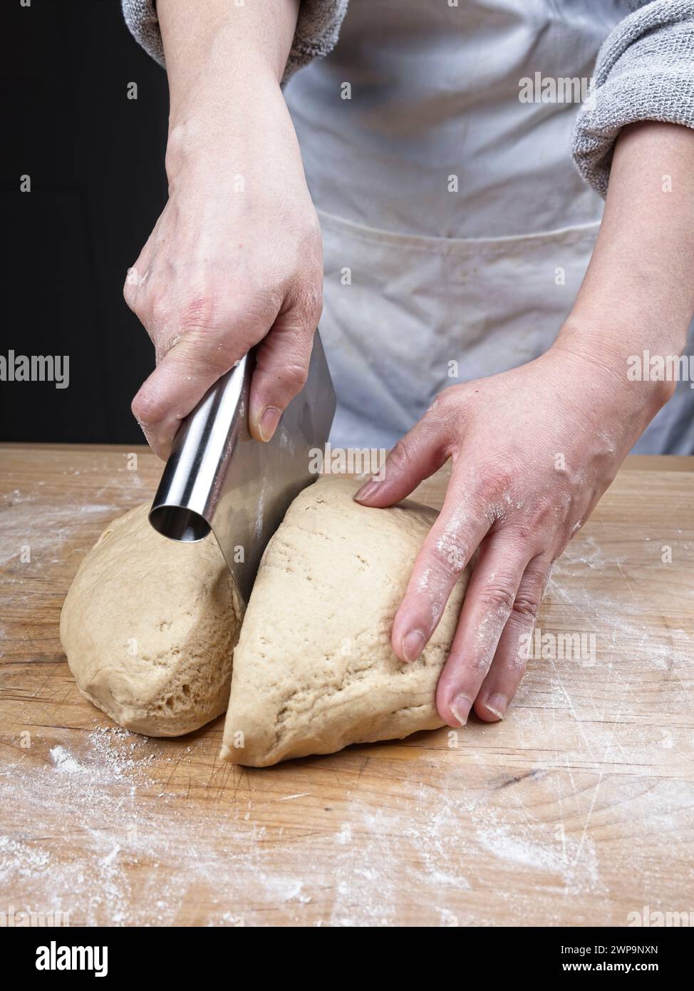 A close up photo of the hands of a woman using a dough cutter to cut a ...