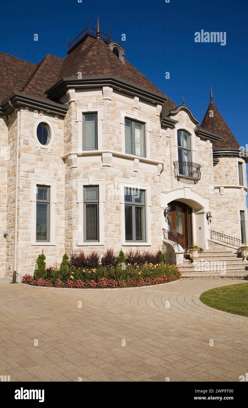 Partial view of luxurious two story beige and tan cut stone home with ...