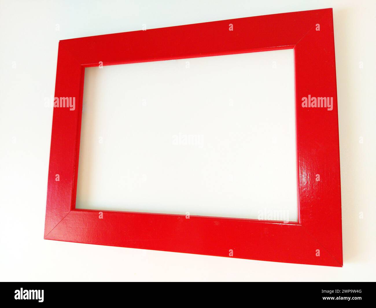 Red photo frame on a white background. The frame is photographed at an ...