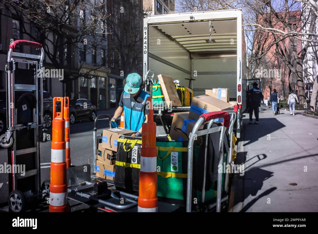 An Amazon worker sorts deliveries in the street for distribution in the ...
