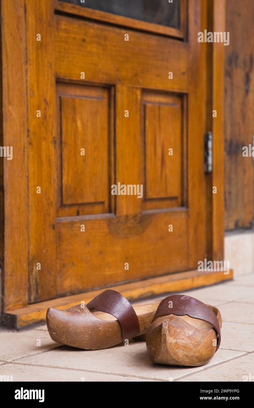 Pair of old clogs with brown leather strap in front of back entrance ...