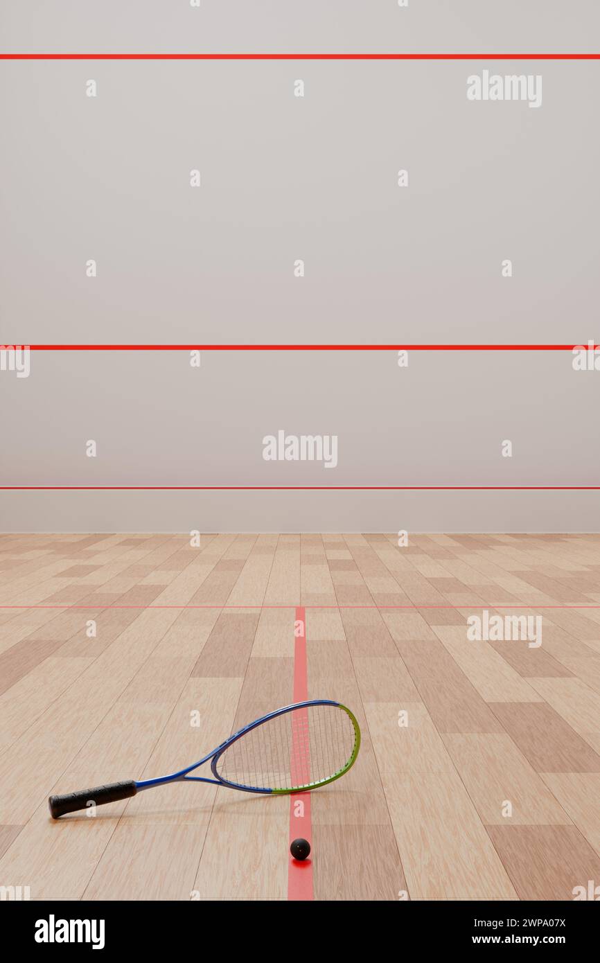 A racket and a squash ball are lying on the court floor in the sports ...