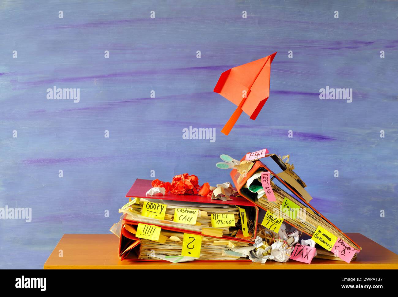 Messy file folder,sticky notes and paper plane taking off. Red tape ...
