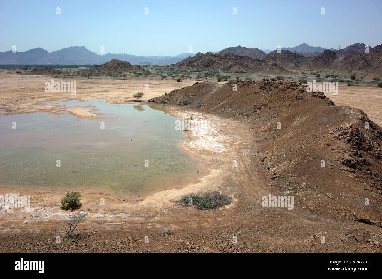 Arabian peninsula landscape with cracked mud, puddle and dry mountains ...