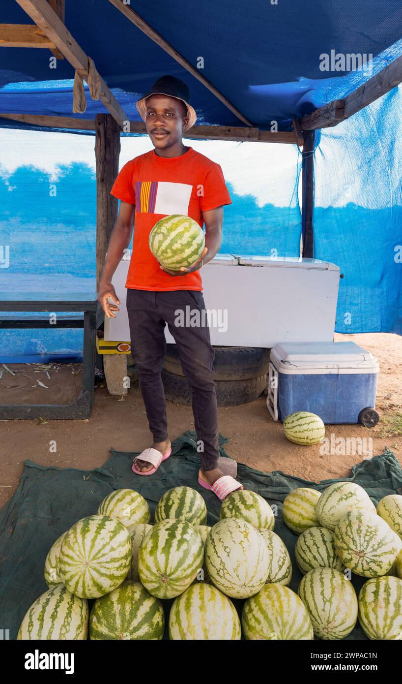 african street vendor selling watermelons on the side of the road in a ...