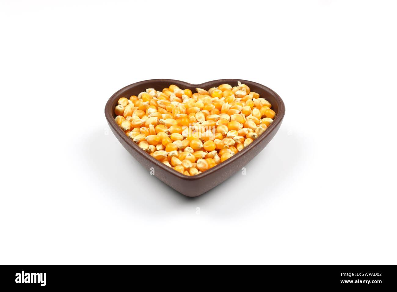 Unpopped popcorn in a wooden bowl on white background. A type of corn ...