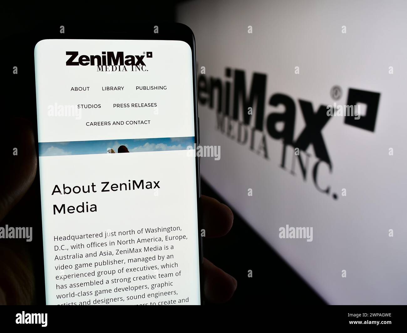 Person holding cellphone with webpage of US video game company ZeniMax ...