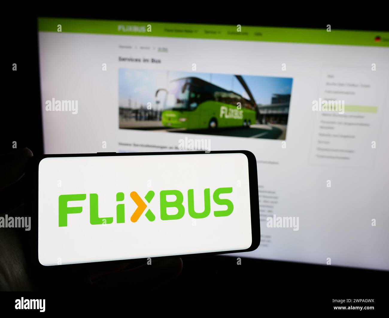 Person holding mobile phone with logo of German long-distance bus ...