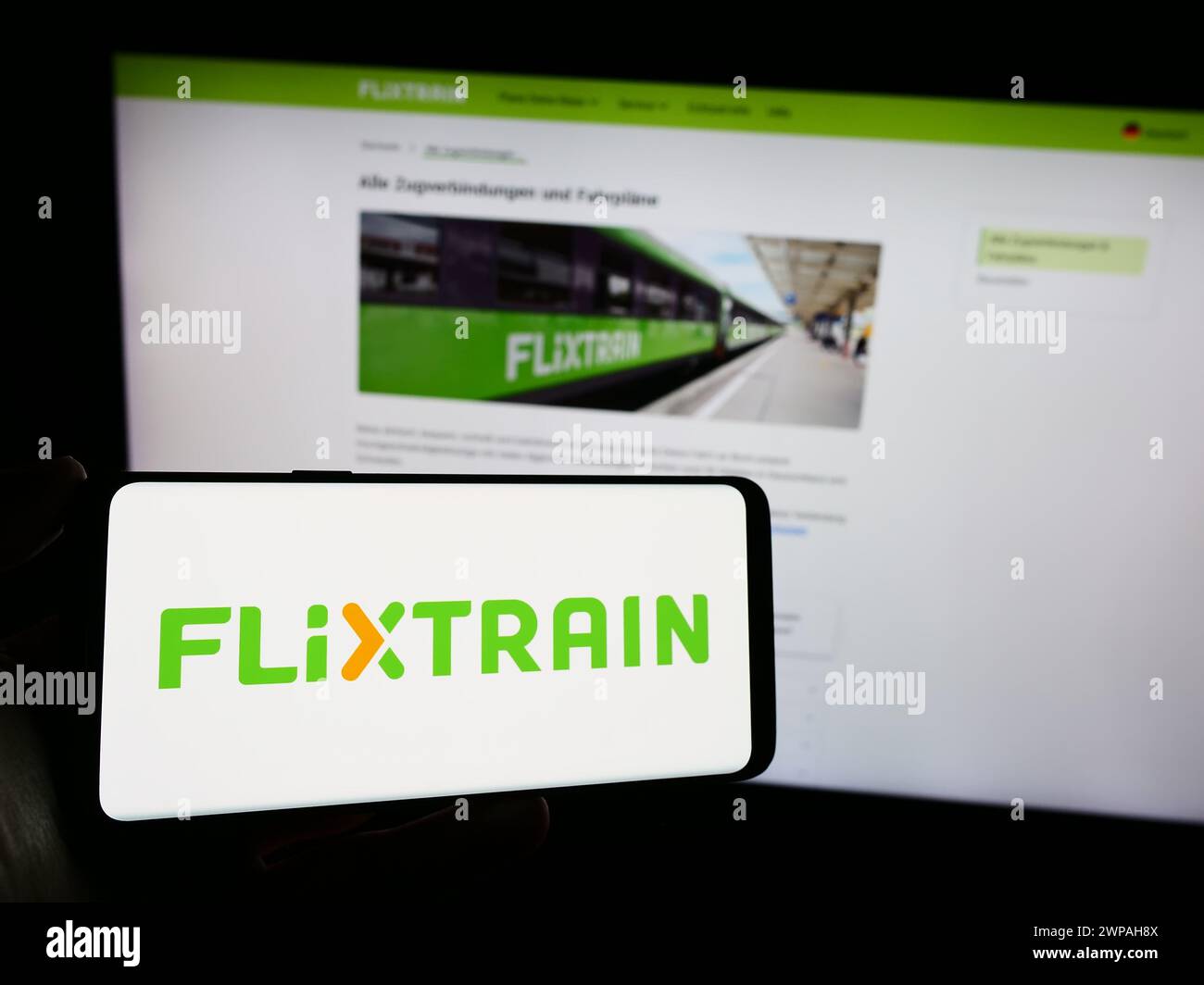 Person holding mobile phone with logo of German long-distance railway ...