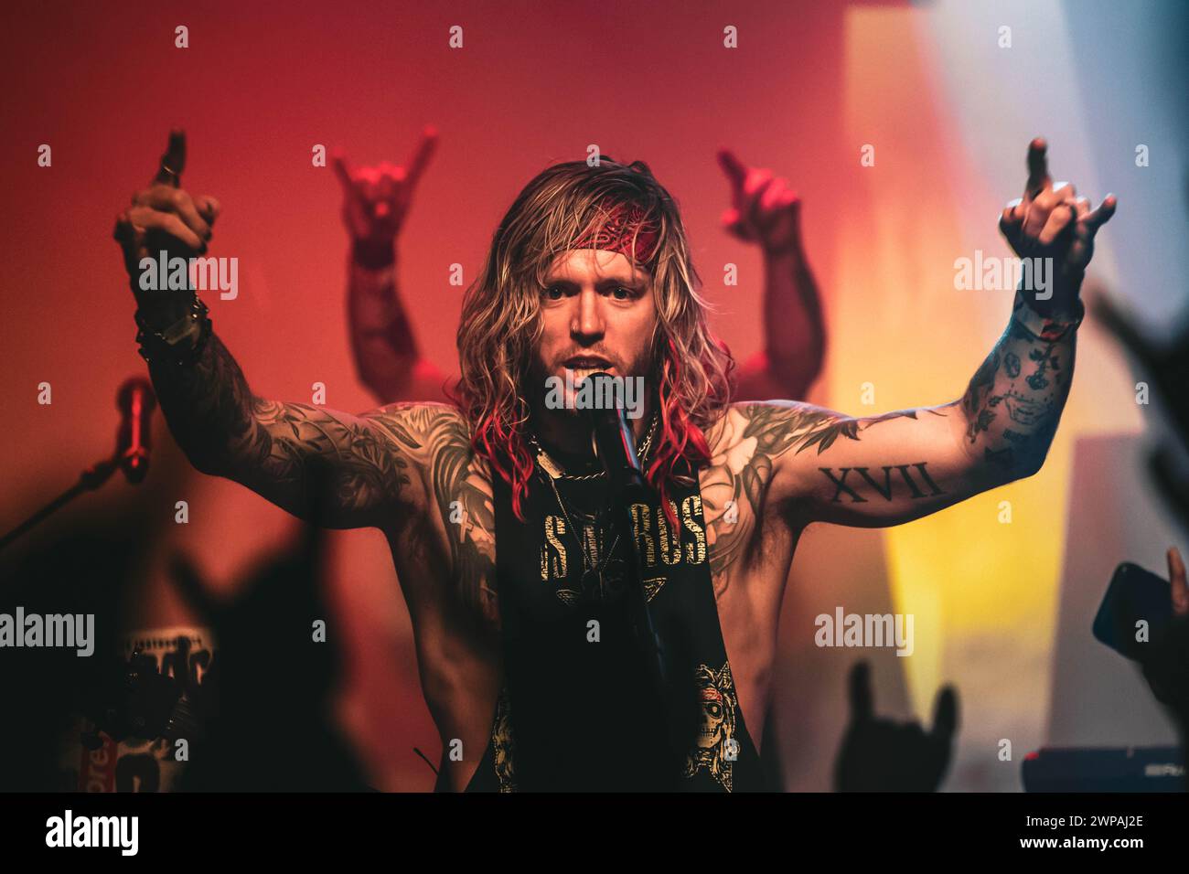 Rock band singer performing on stage with arms raised Stock Photo - Alamy