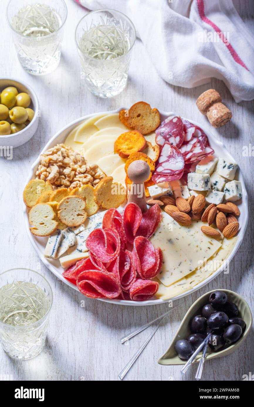 Aperitif, champagne and snack of sausage, cheese, nuts, olives and ...