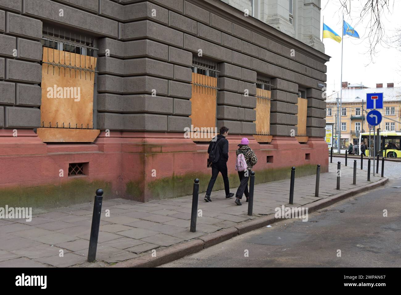 People walk past windows boarded up against missile attacks in the centre of Lviv city, Ukraine ...