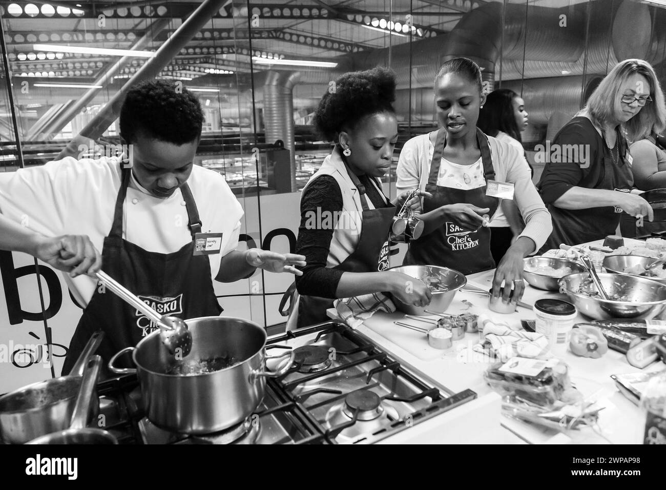 Group of people preparing a variety of dishes at a crowded cooking ...