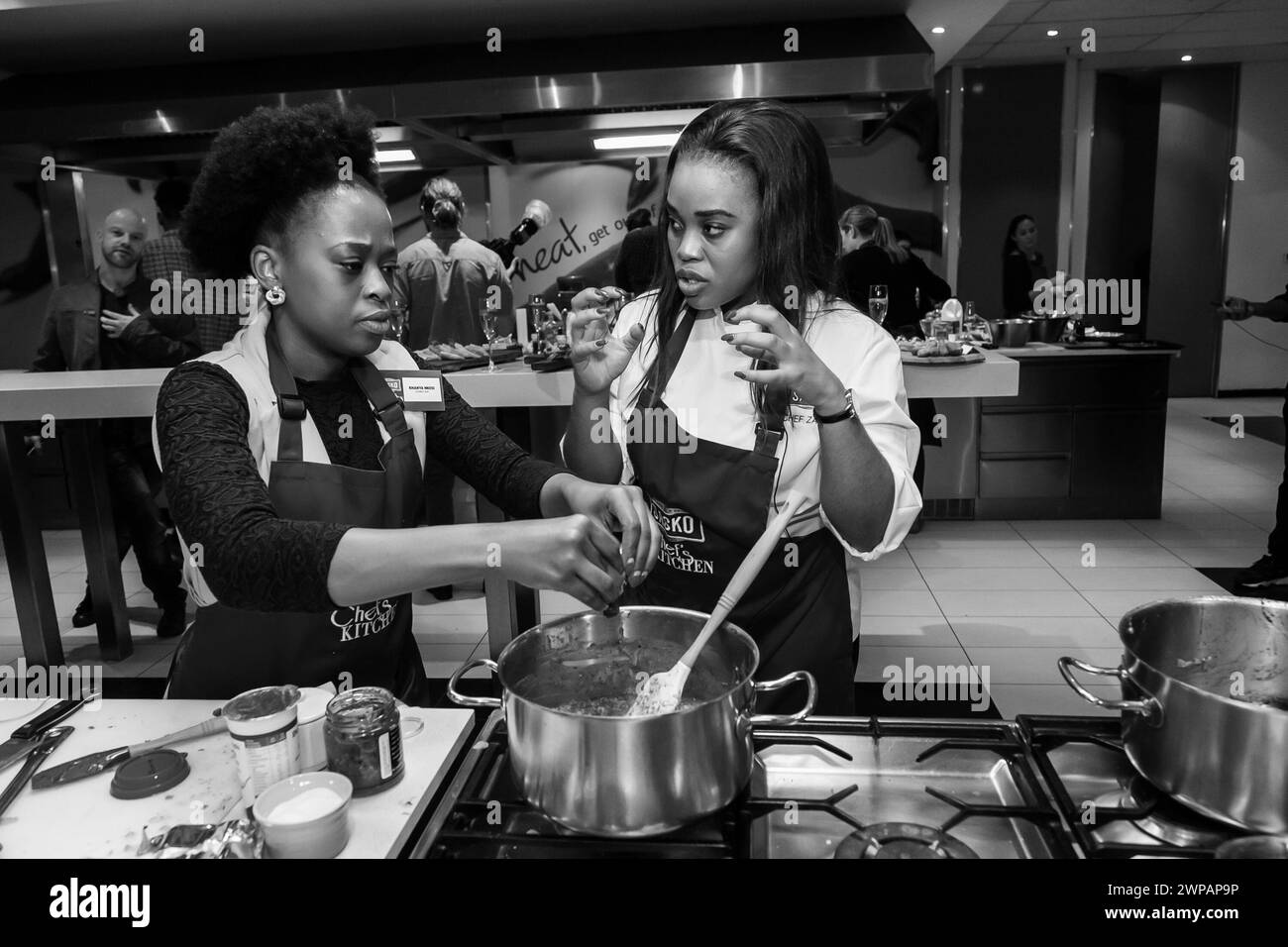 Two women in aprons cooking on a stovetop Stock Photo - Alamy