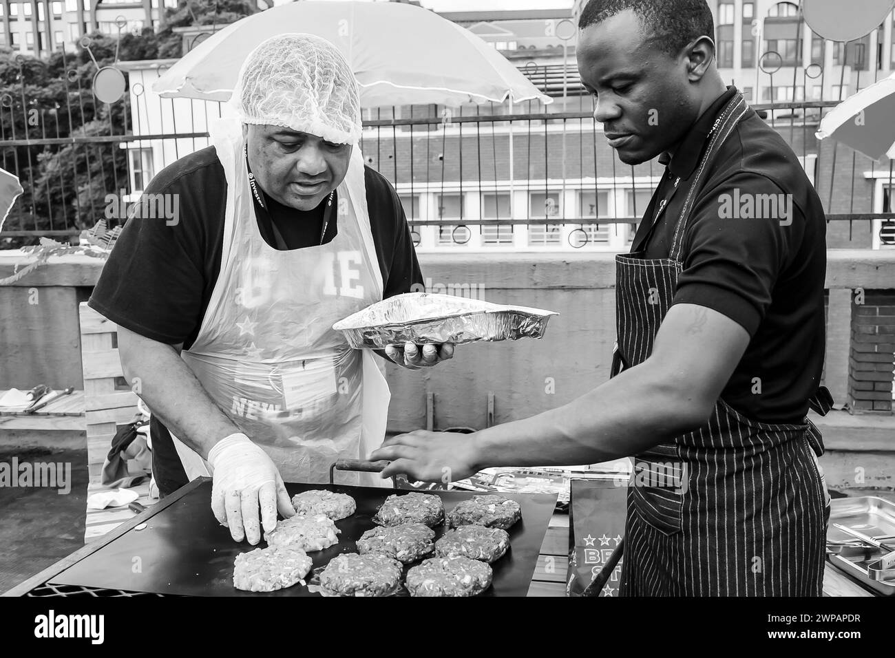 Two men setting up a food tray on a rooftop next to an umbrella Stock ...