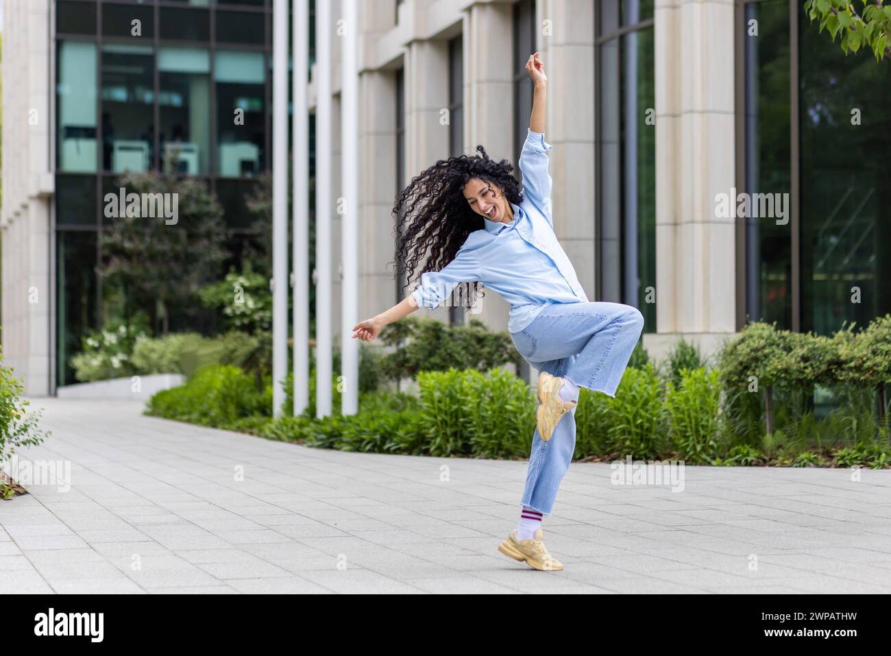 A youthful and vibrant woman is captured in mid-dance, radiating ...