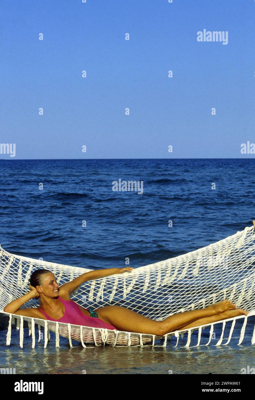 Beauty beach blond hair young woman lay down on hamac front the beach ...