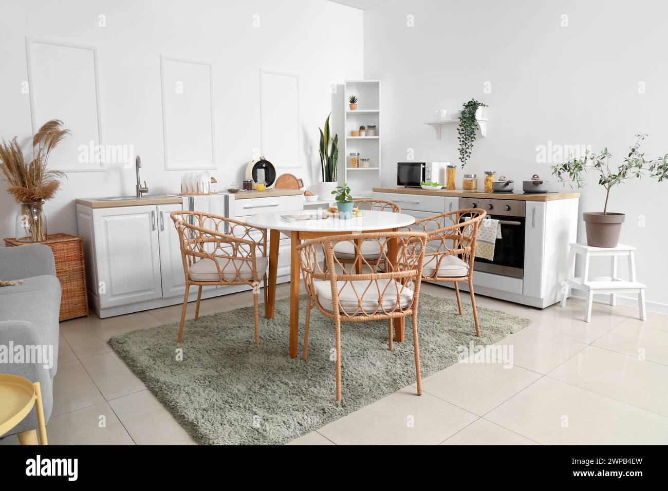 Interior of light kitchen with green plants, counters and dining table ...