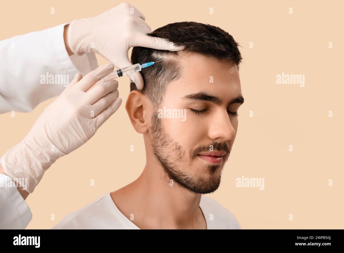 Young man receiving injection for hair growth on beige background ...