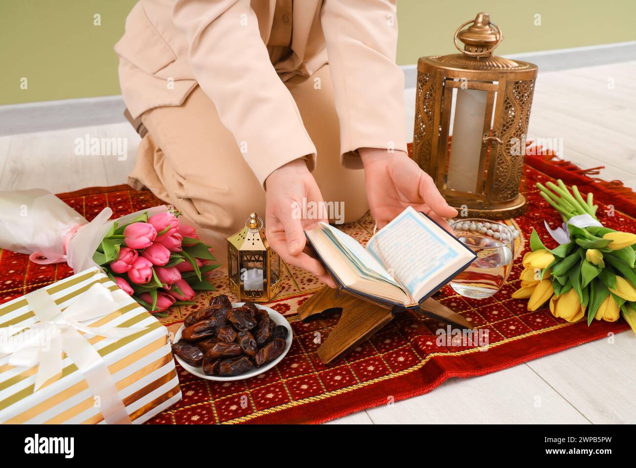 Mature Muslim woman with Koran praying on mat near green wall, closeup ...
